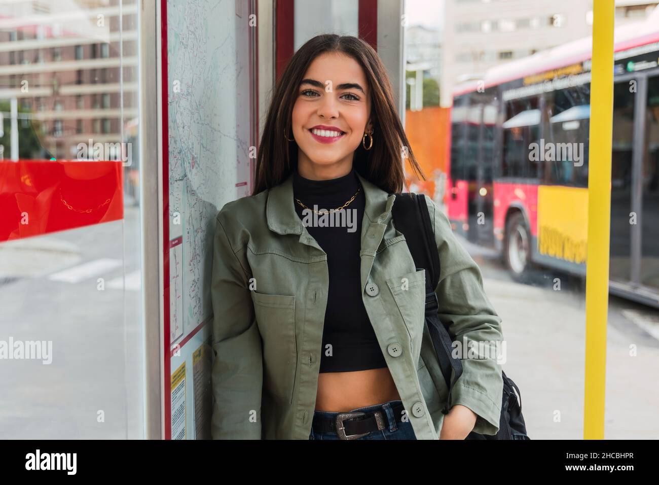 Smiling woman with jacket at bus stop Stock Photo - Alamy