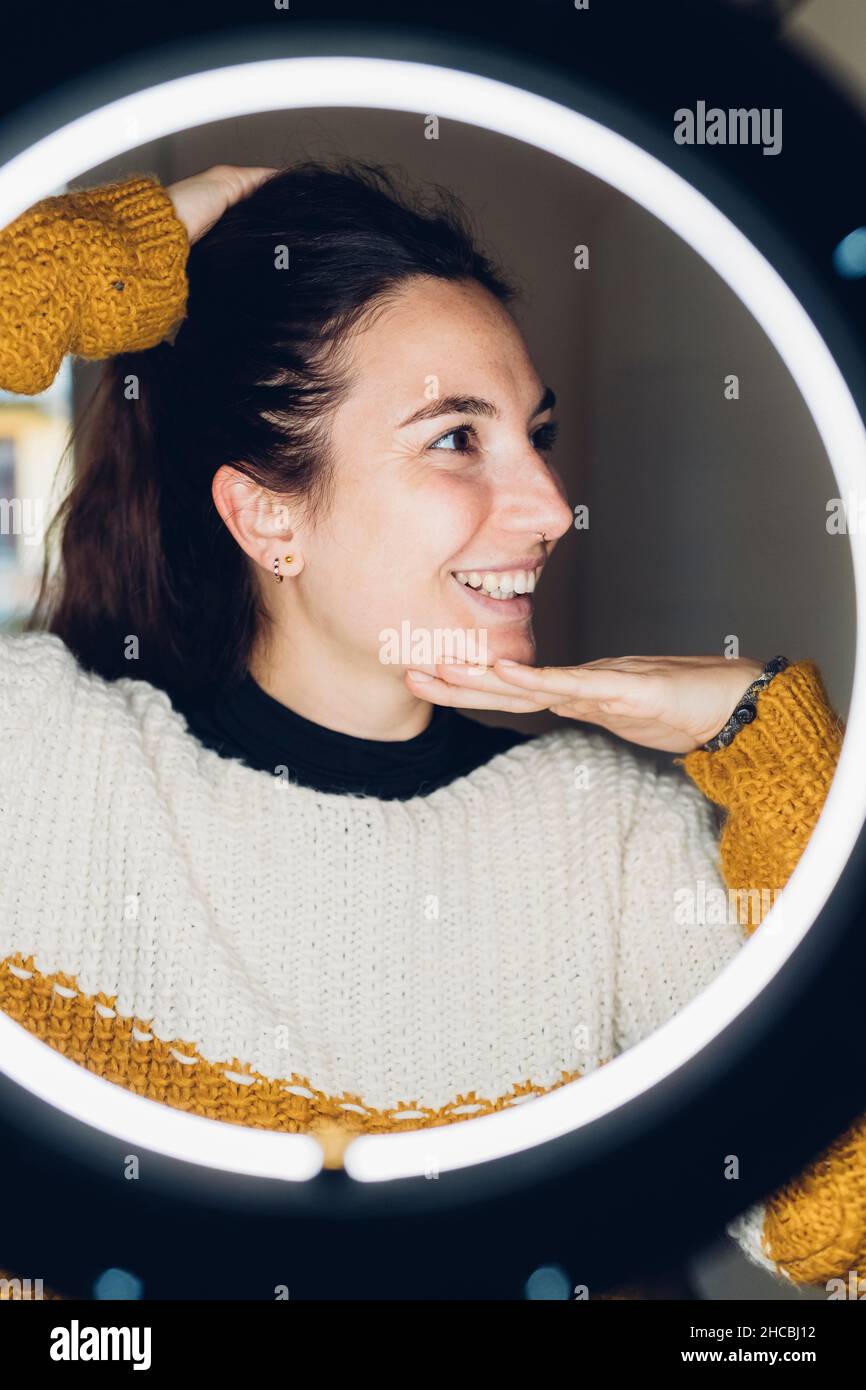 Smiling influencer touching face in front of ring light Stock Photo - Alamy