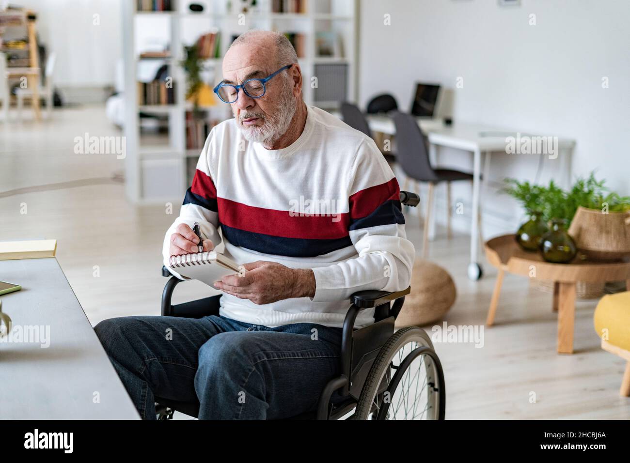 Serious disabled man holding diary at home office Stock Photo - Alamy