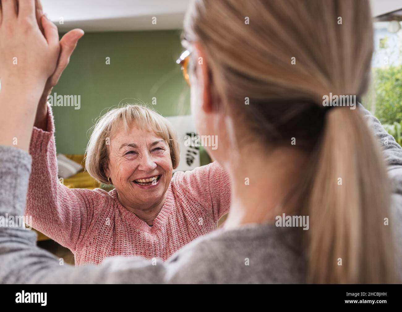 Senior woman giving high-five to caregiver at home Stock Photo - Alamy