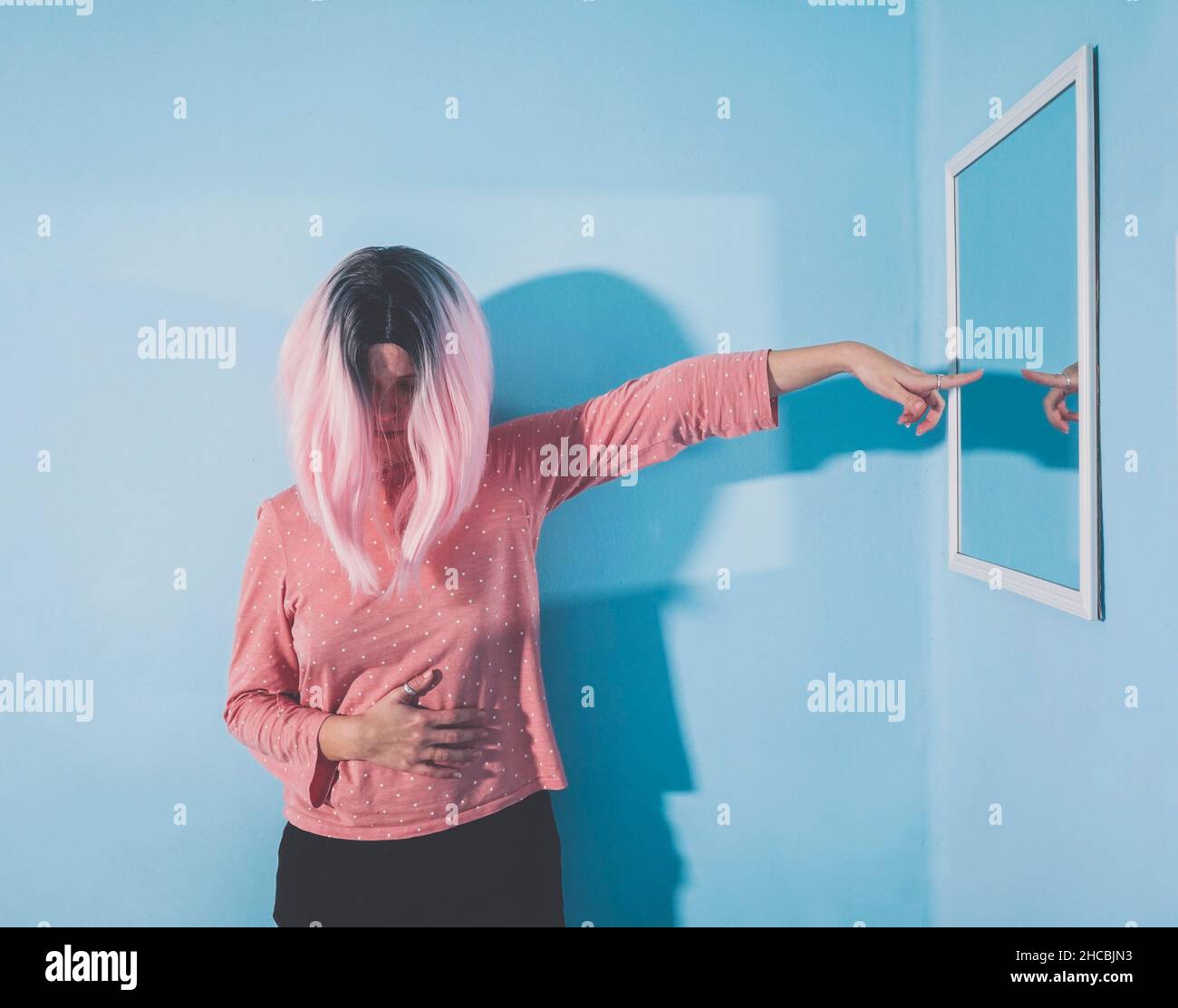 Woman pointing at mirror on wall Stock Photo - Alamy