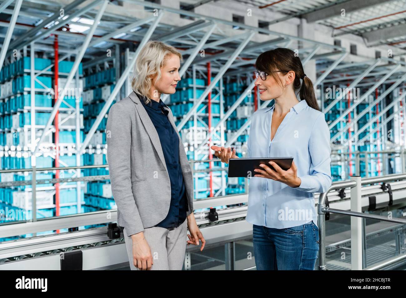 Manager having discussion with coworker in warehouse Stock Photo - Alamy