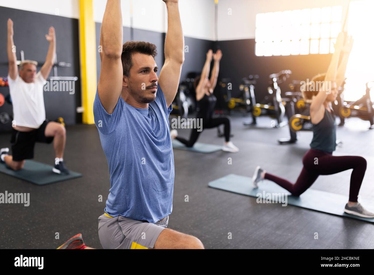 Coach with arms raised assisting athletes practicing in gym Stock Photo ...