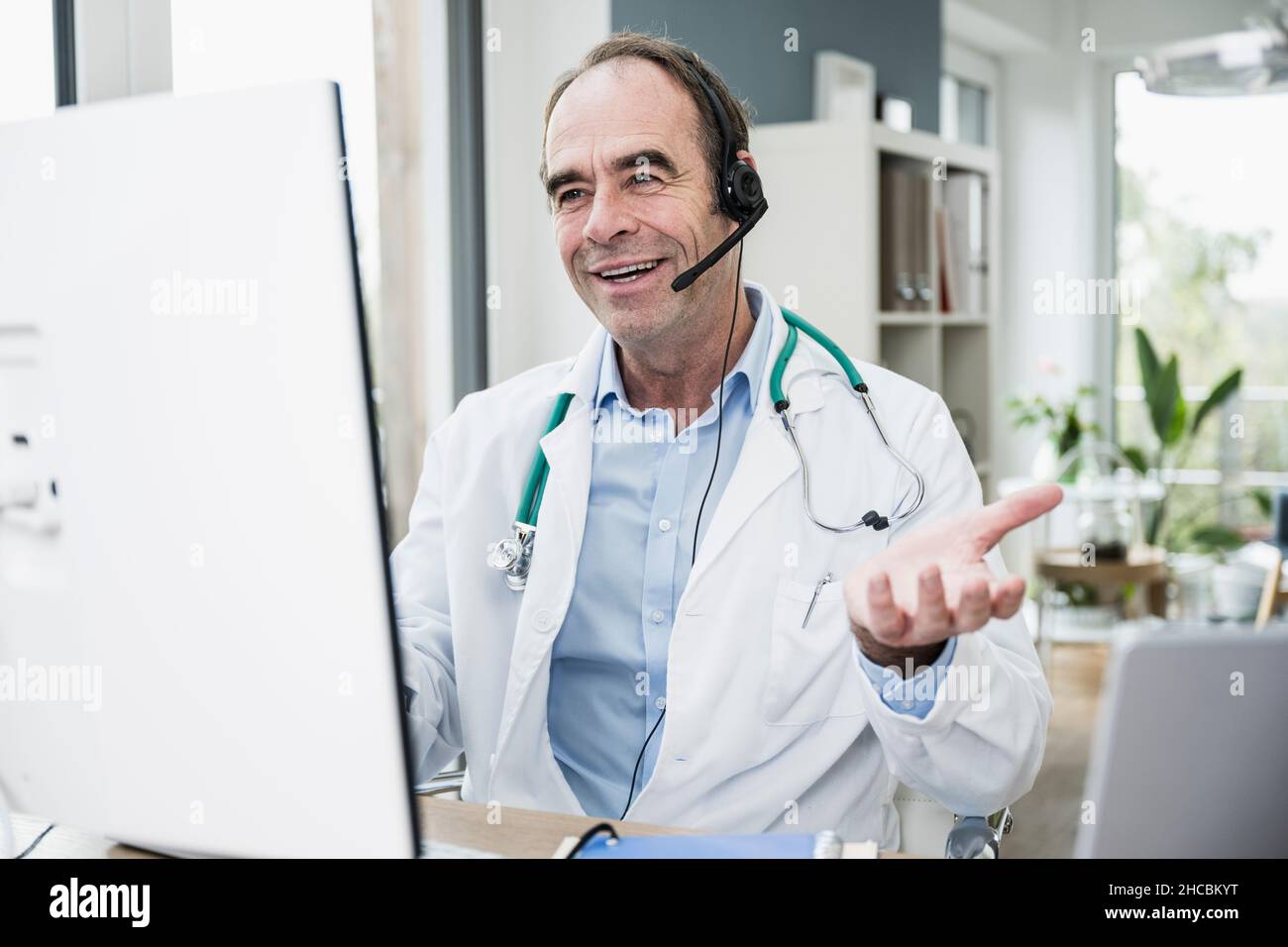 Smiling doctor gesturing on video call at clinic Stock Photo - Alamy