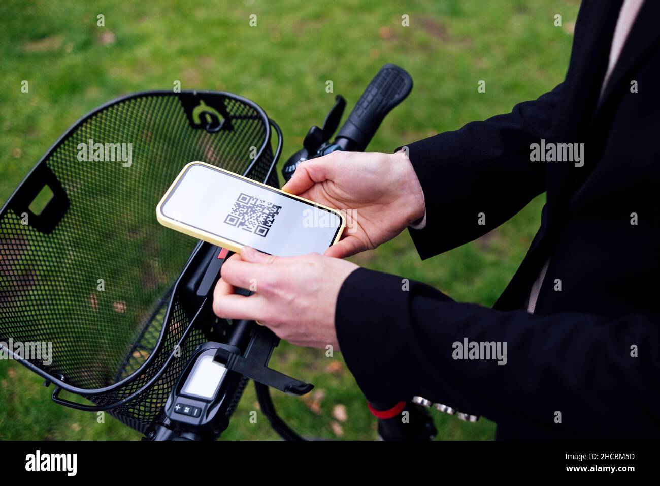Businesswoman scanning QR code on electric bicycle with smart phone ...
