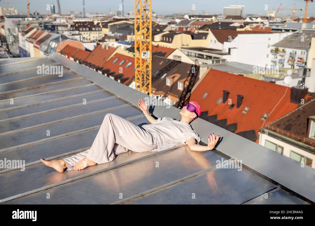 Woman with eye mask sunbathing on rooftop Stock Photo - Alamy