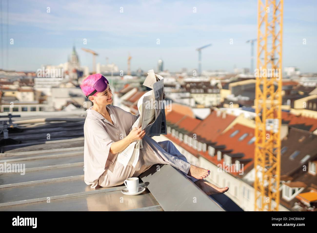 Smiling woman sitting on rooftop reading newspaper Stock Photo - Alamy