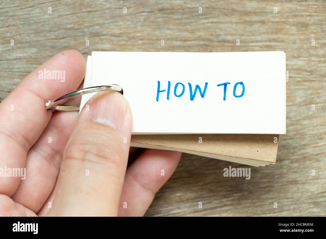 Man hold the flash card with handwriting word how to on wood background ...