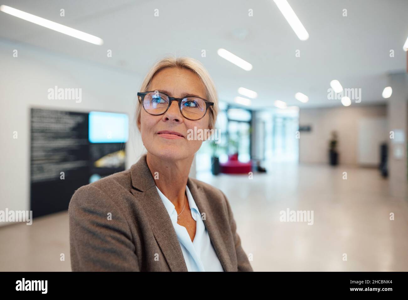 Businesswoman with arms crossed reading screen in office Stock Photo ...