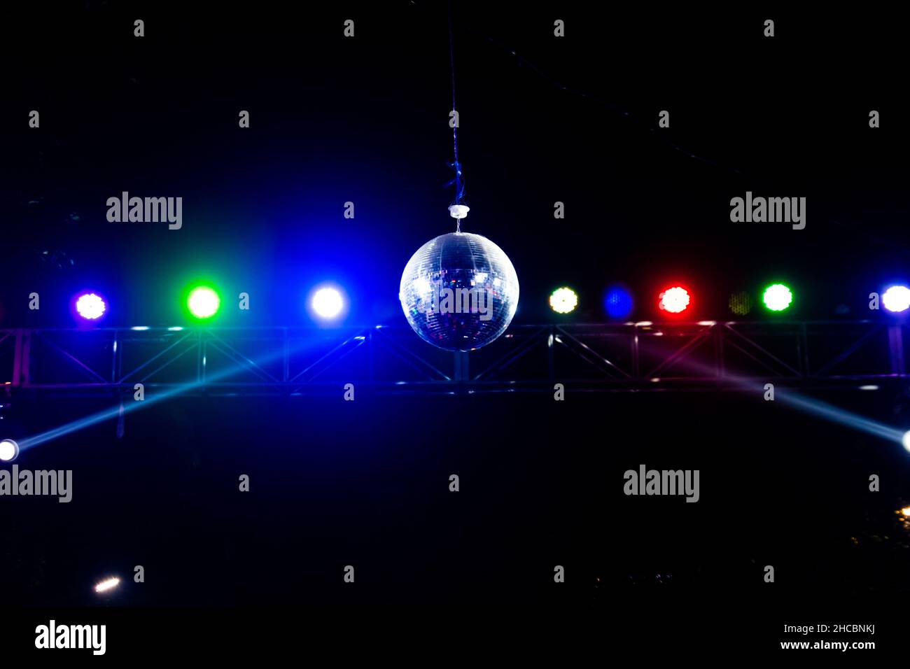 A row of colorful lights falling on a disco ball marking a party ...
