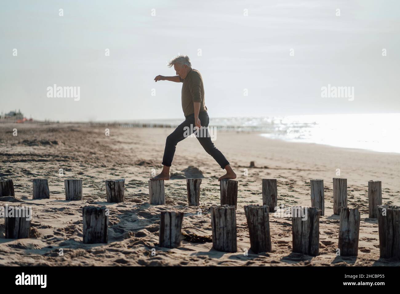 Carefree senior man balancing on wooden posts at beach Stock Photo - Alamy
