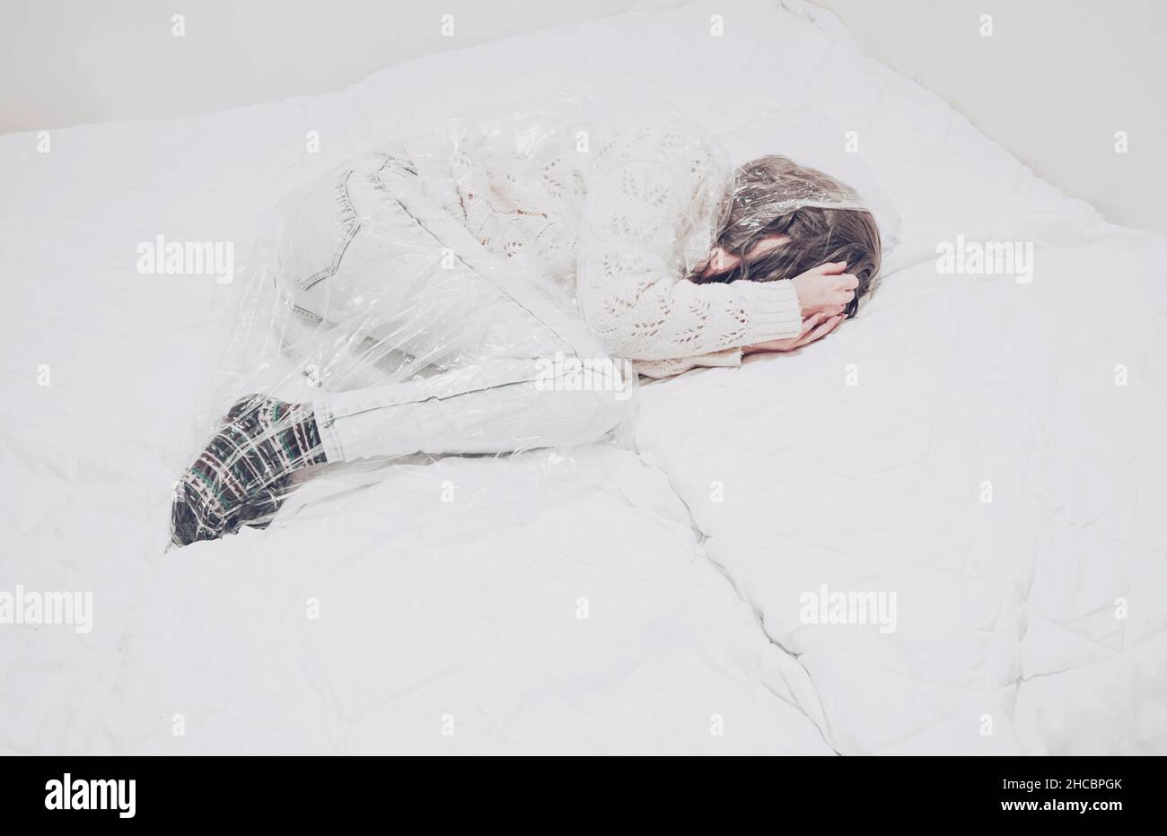 Woman trapped in plastic lying on duvet in confined place Stock Photo ...