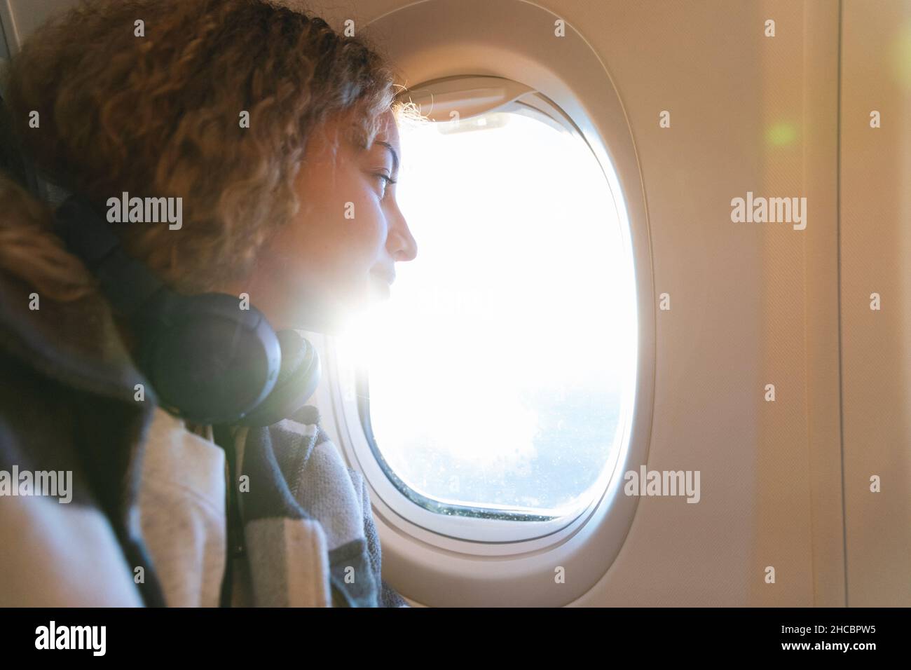 Young woman looking out of airplane window Stock Photo - Alamy