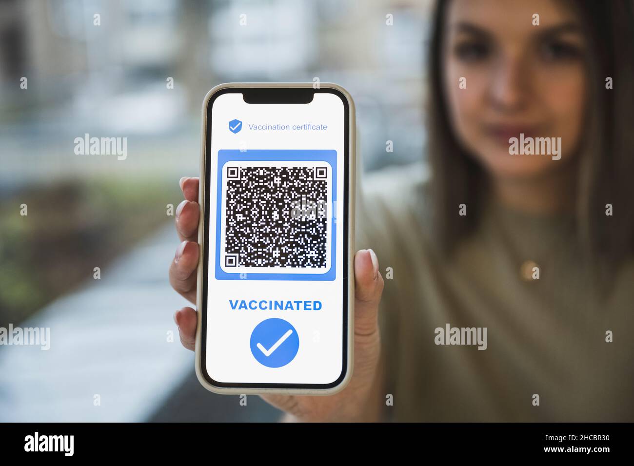 Woman holding mobile phone with QR code and check mark symbol on screen ...