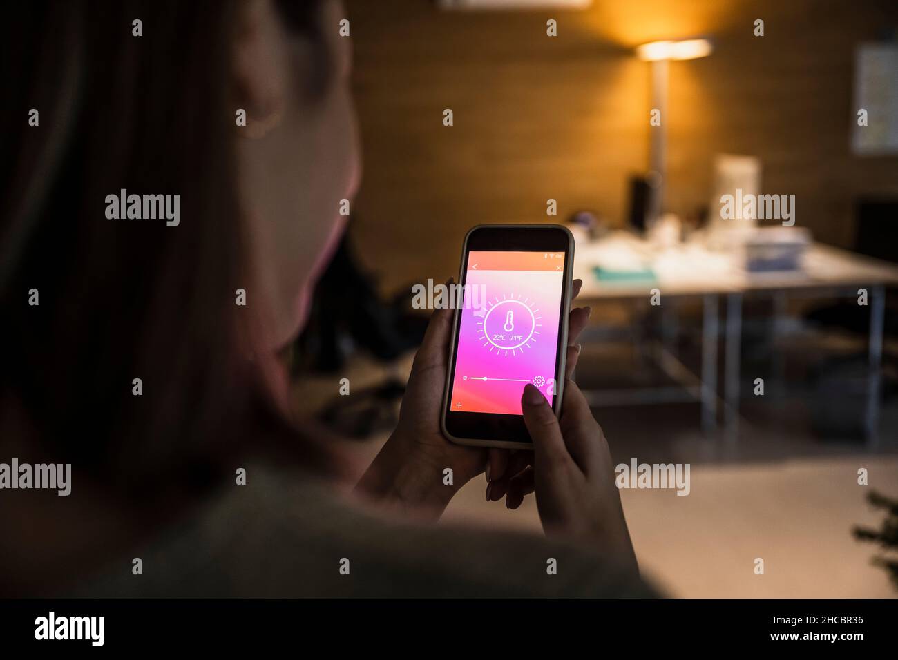 Woman controlling temperature through smart phone at home Stock Photo ...