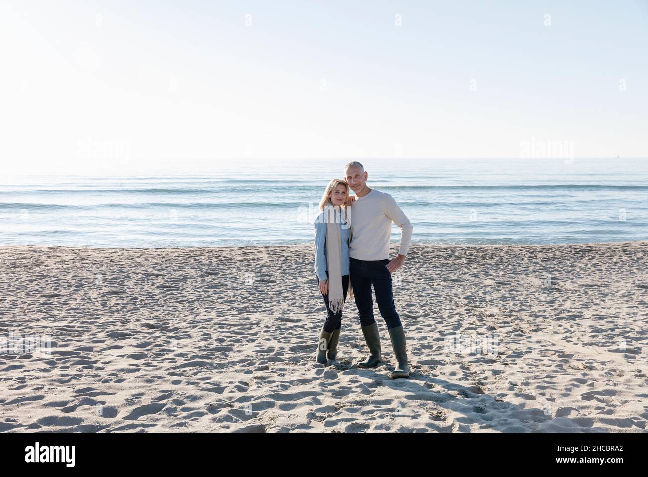 Couple standing together on sand at beach Stock Photo - Alamy