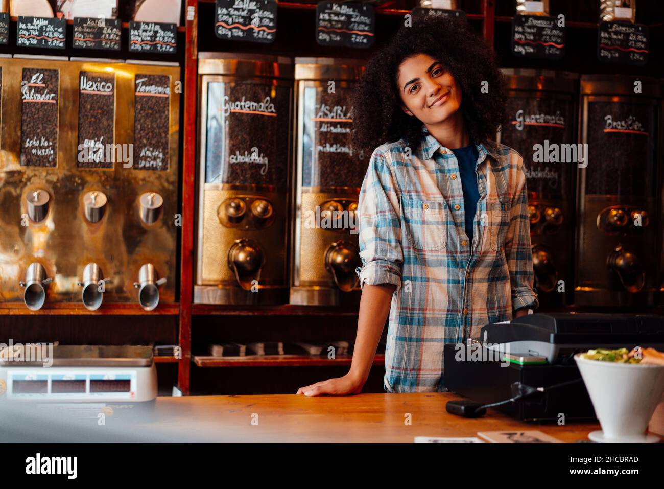 Smiling owner standing at cash register in coffee roastery Stock Photo ...