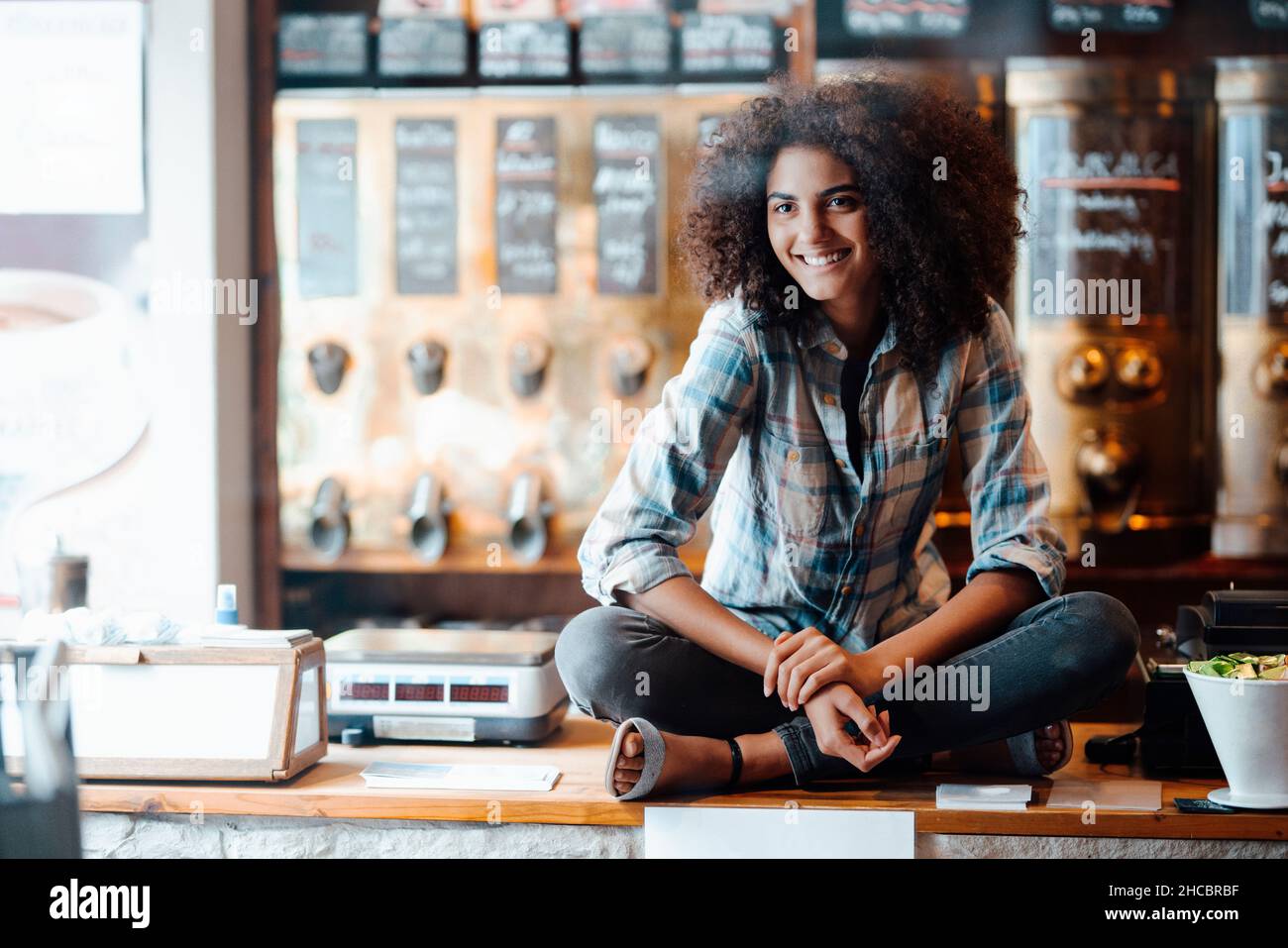 Businesswoman sitting cross-legged on counter at coffee roastery Stock ...