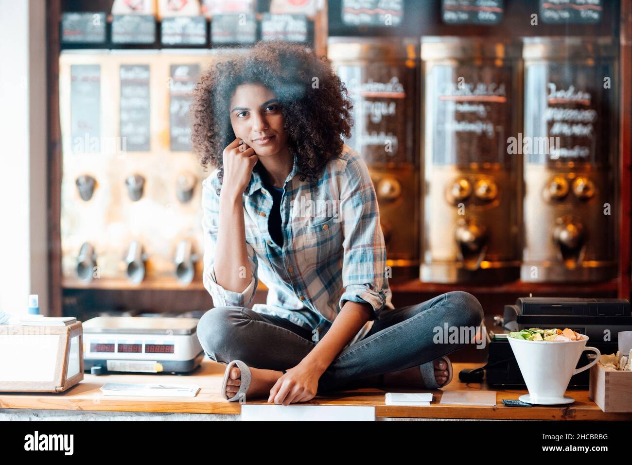 Roastery owner sitting cross-legged on counter Stock Photo - Alamy