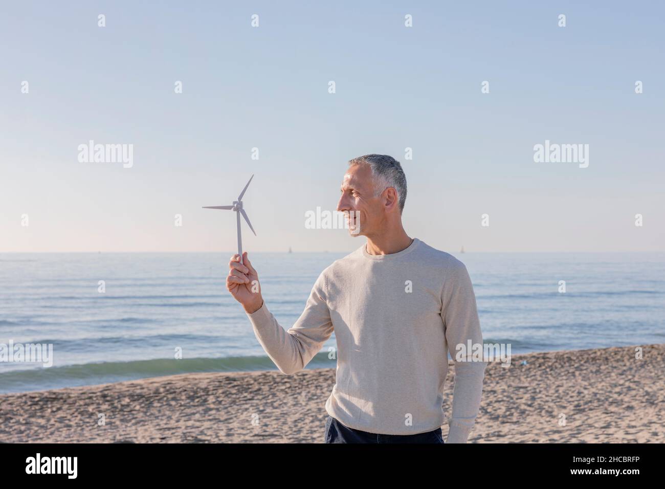 Man looking at wind turbine model standing on beach Stock Photo - Alamy