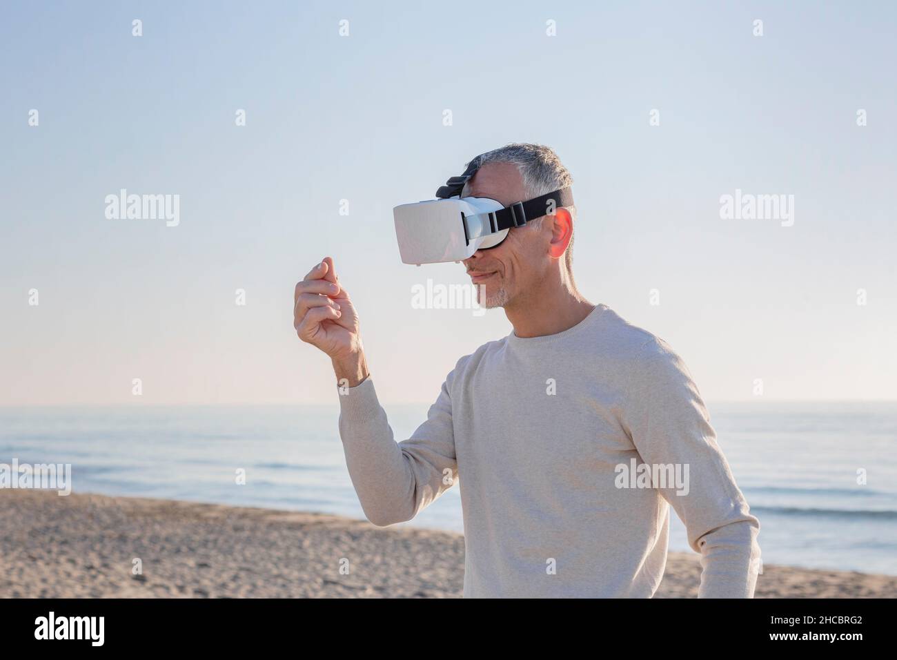 Man wearing virtual reality headset gesturing at beach Stock Photo - Alamy