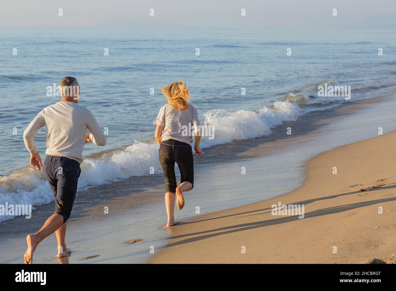 Man running after woman on shore at beach Stock Photo - Alamy