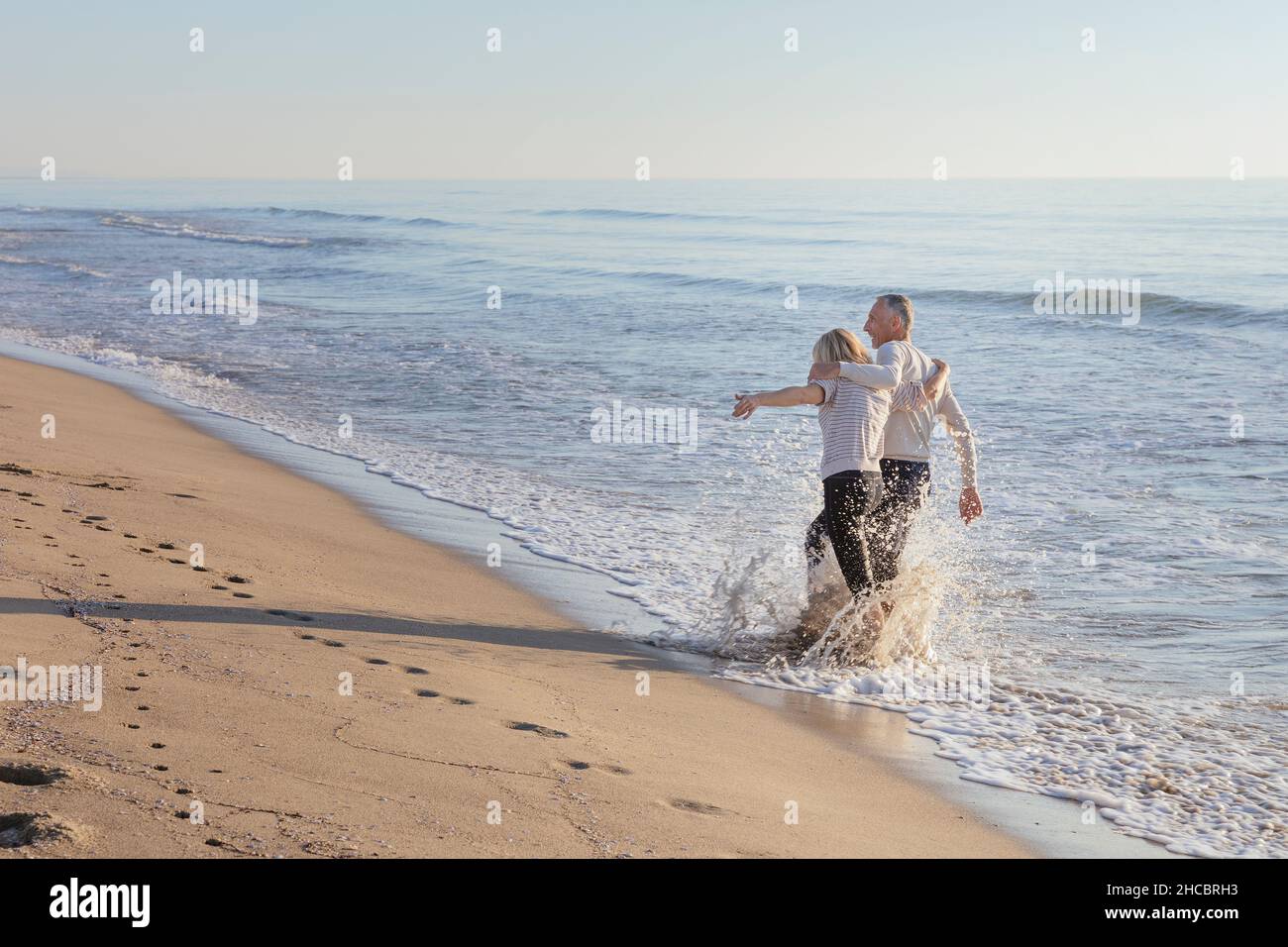 Couple splashing water on each other at beach Stock Photo - Alamy