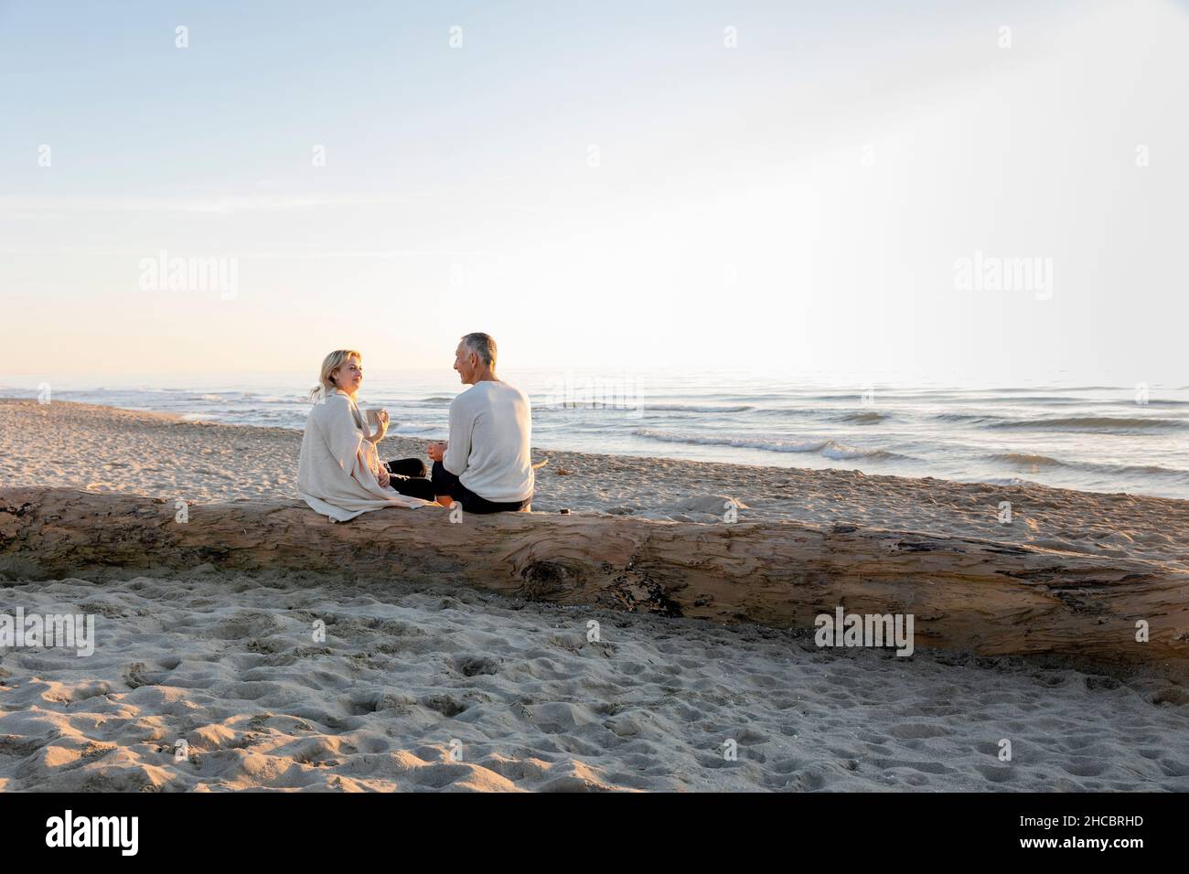 Man and woman sitting on tree log Stock Photo - Alamy