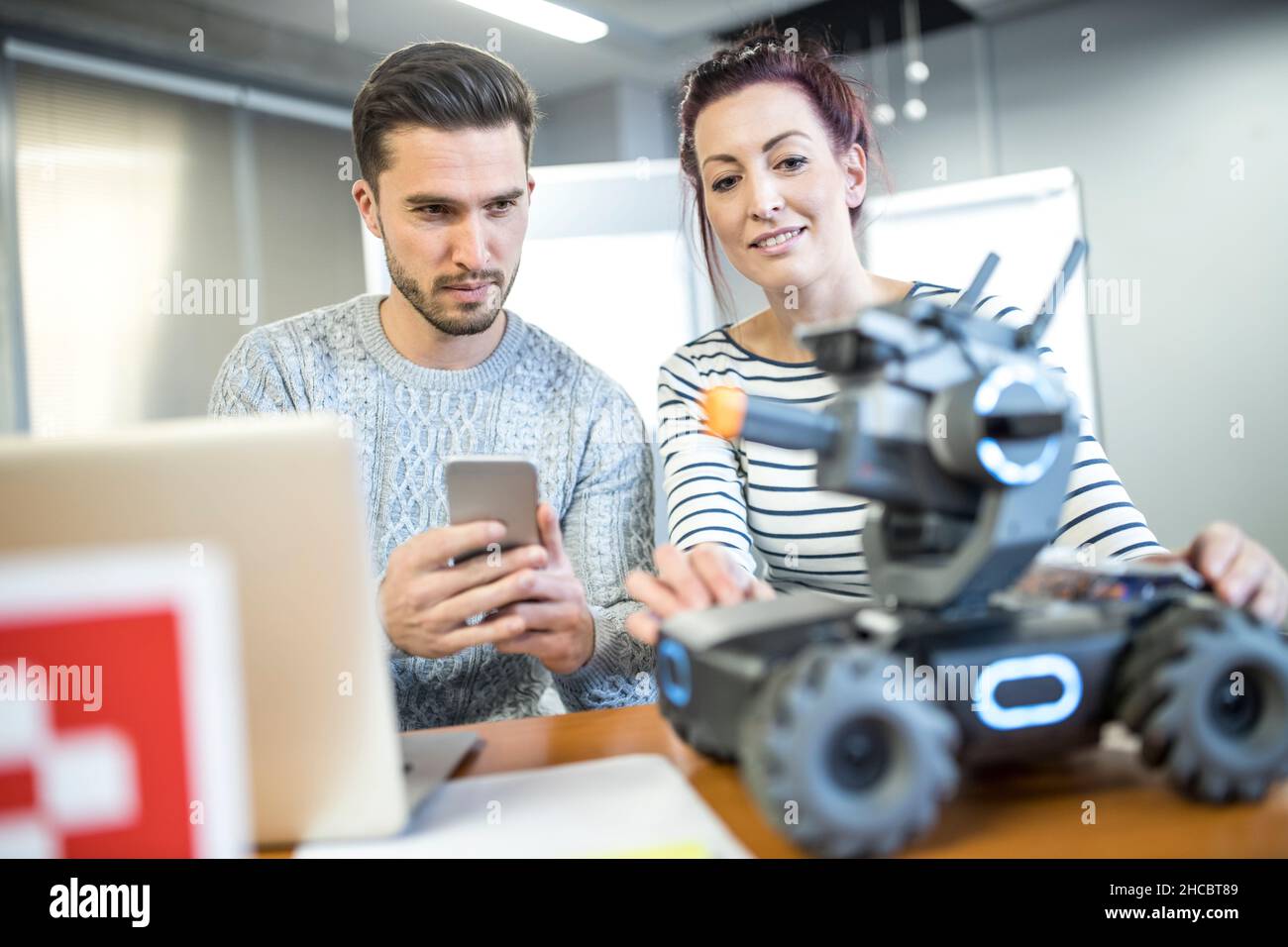 Engineer checking robotic combat tank with colleague at workshop Stock ...