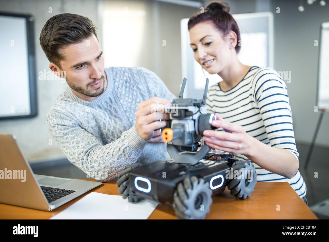 Concentrated engineers fixing electrical part on robotic combat tank at ...