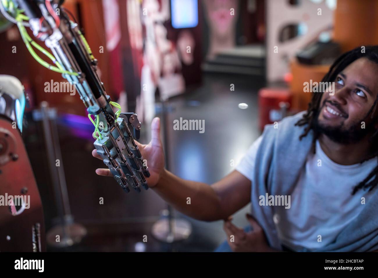 Young tech developer shaking hand with robotic arm at workshop Stock ...