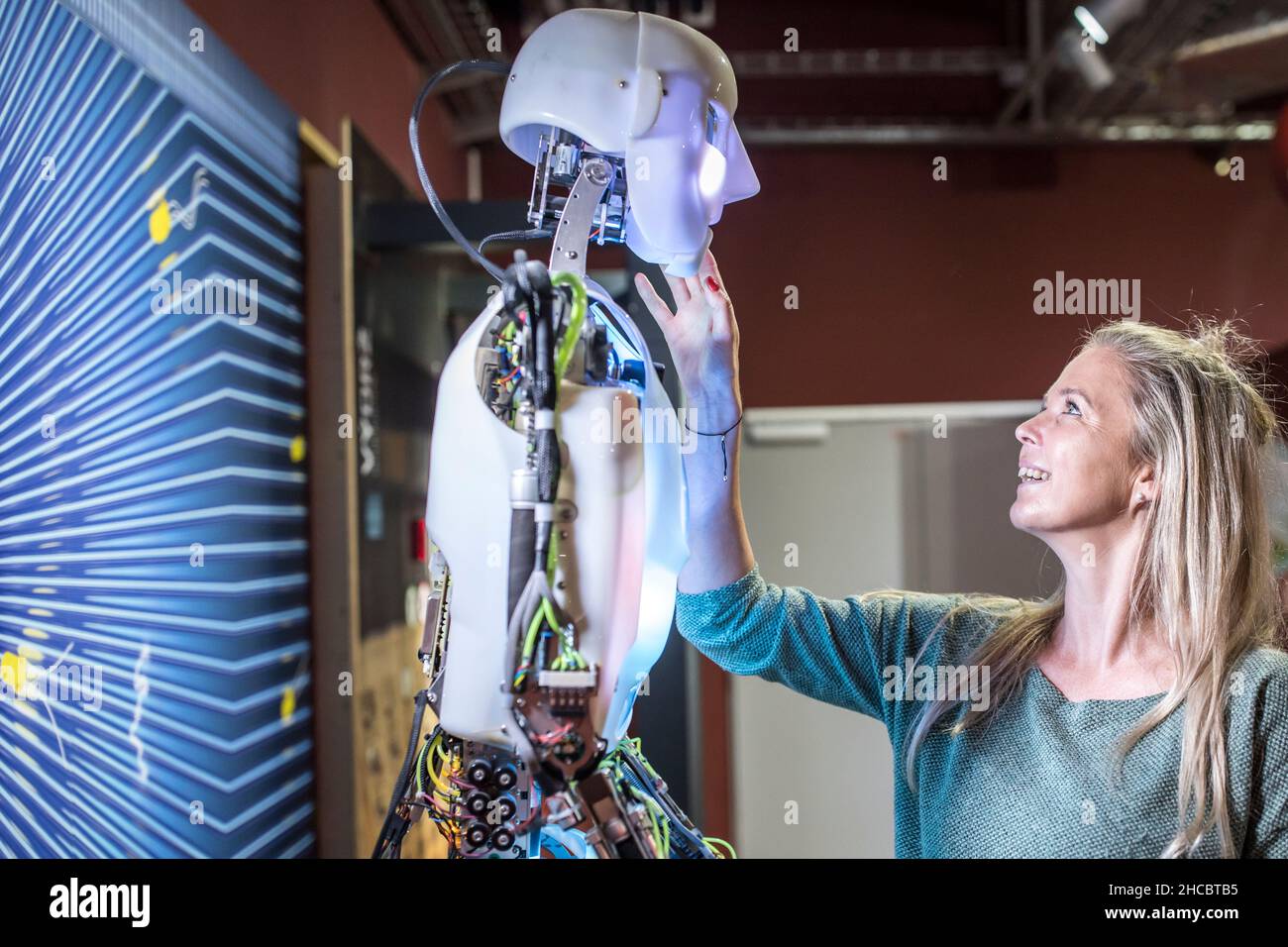 Smiling tech developer touching human robot face at workshop Stock ...