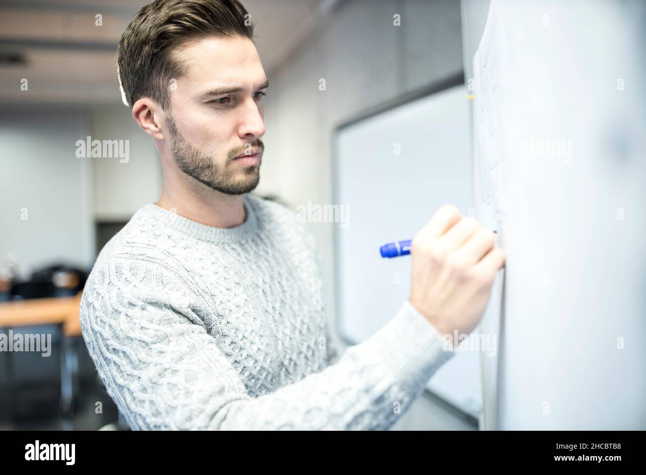 Serious technician writing on whiteboard at workshop Stock Photo - Alamy