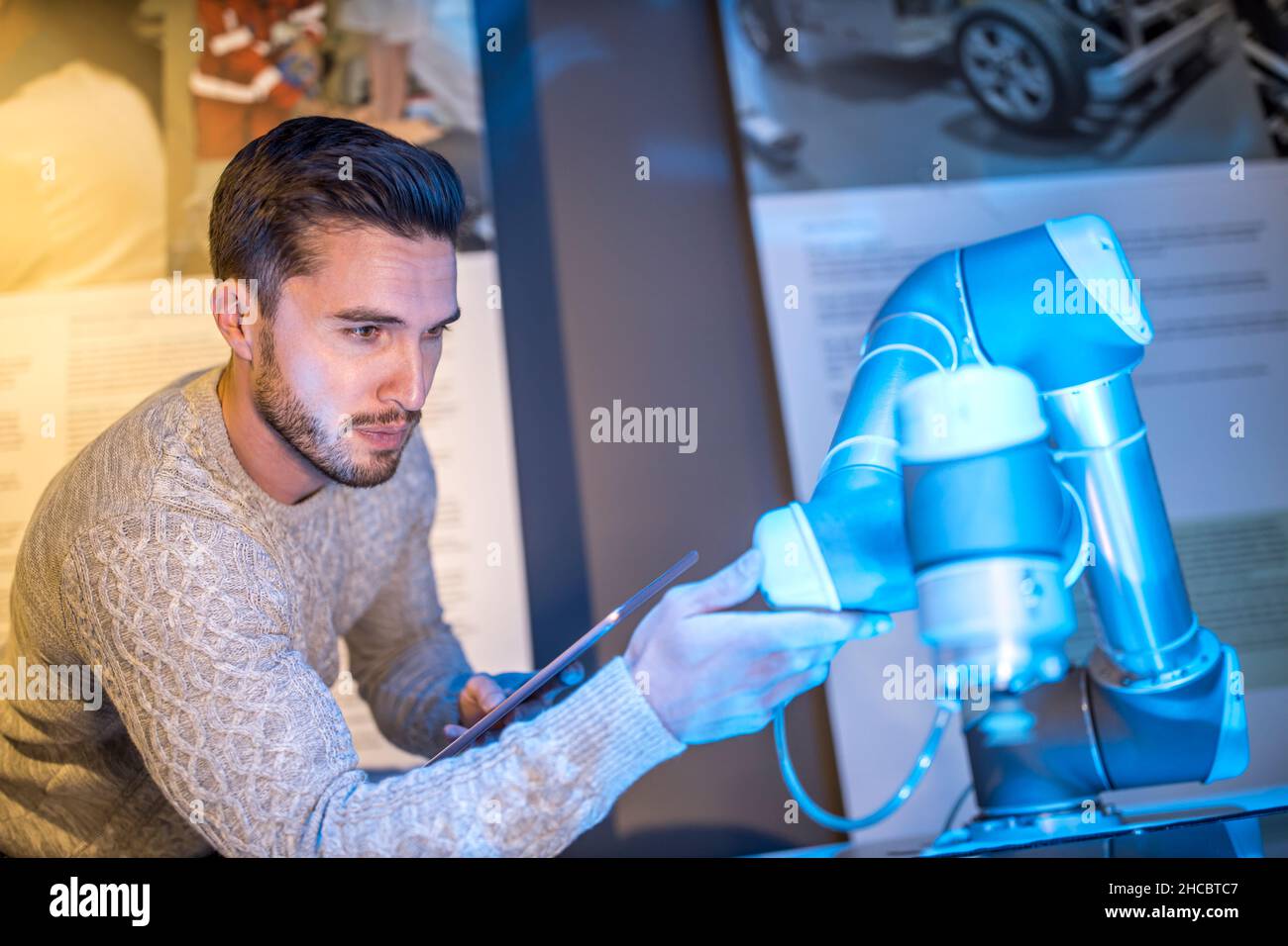 Technician programming robotic arm holding tablet PC at workshop Stock ...