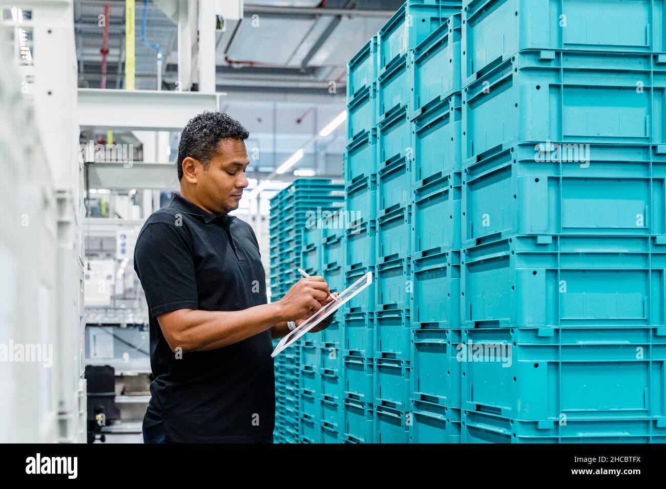 Warehouse worker using tablet PC amidst containers in industry Stock ...