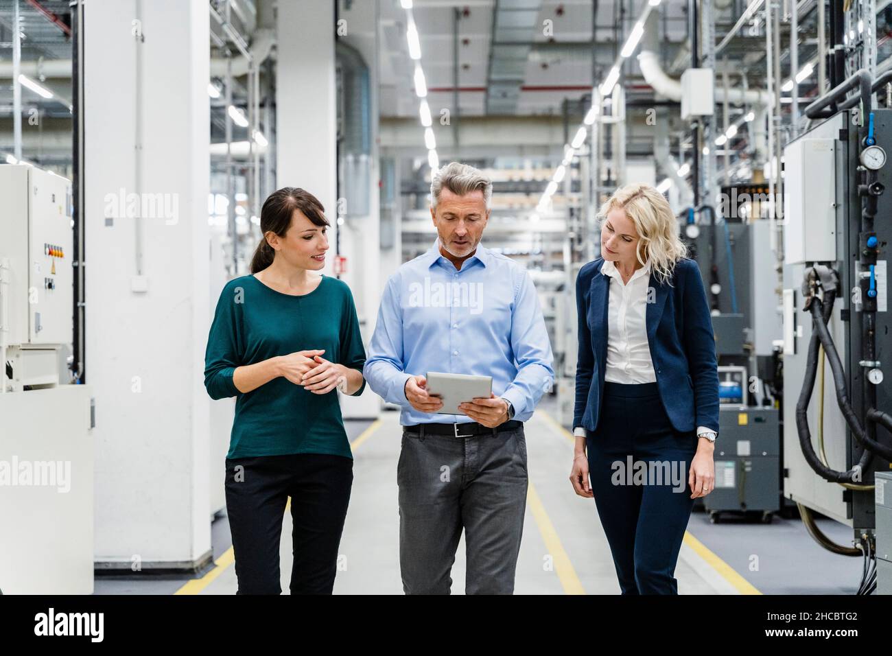 Businessman using tablet PC with coworkers at automated factory Stock ...