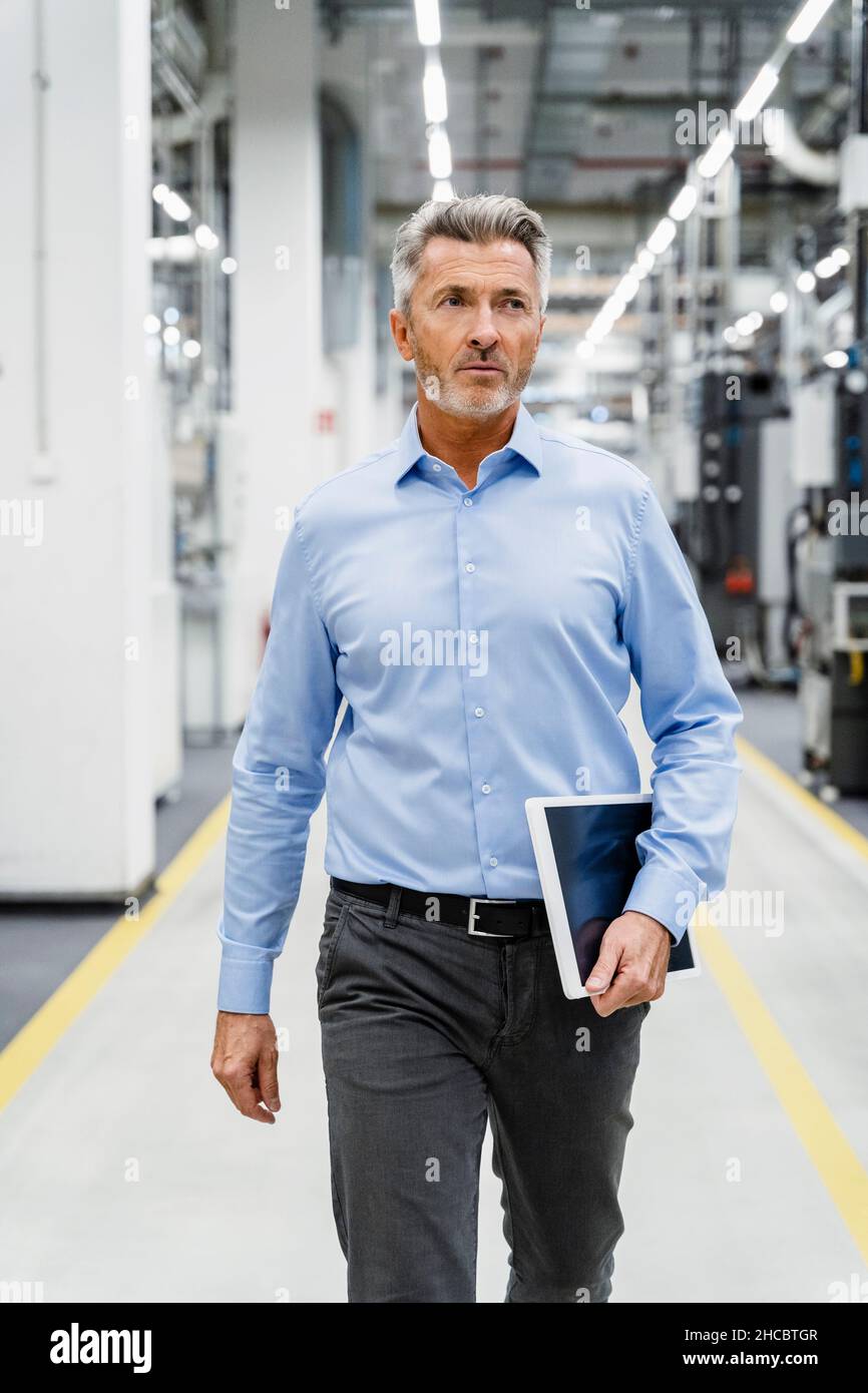 Inspector with tablet PC walking at electrical industry Stock Photo - Alamy