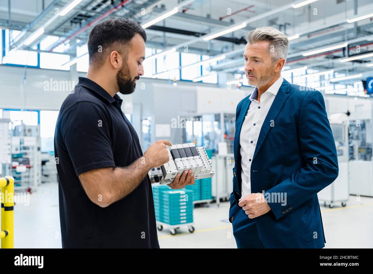 Engineer sharing expertise over equipment with businessman in industry ...