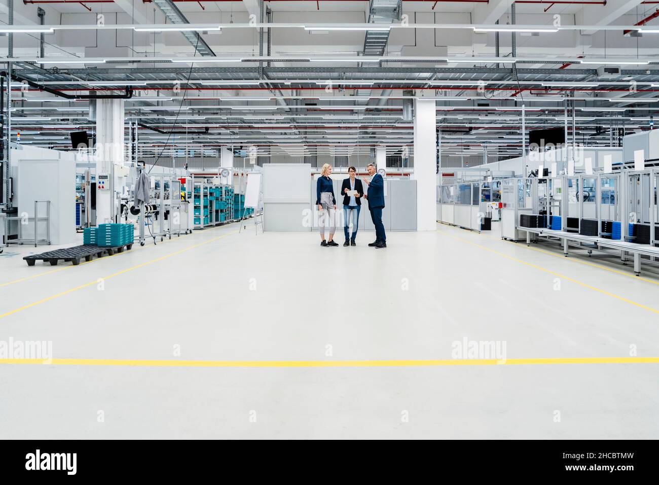 Coworkers having discussion at automated electrical factory Stock Photo ...