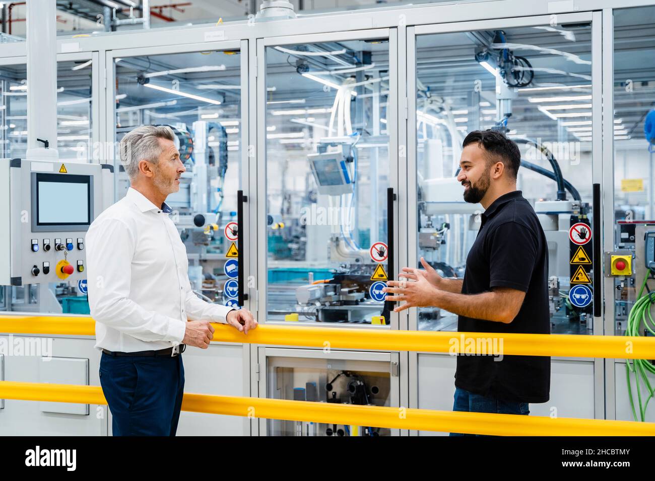Engineer explaining businessman at automated industrial machinery Stock ...
