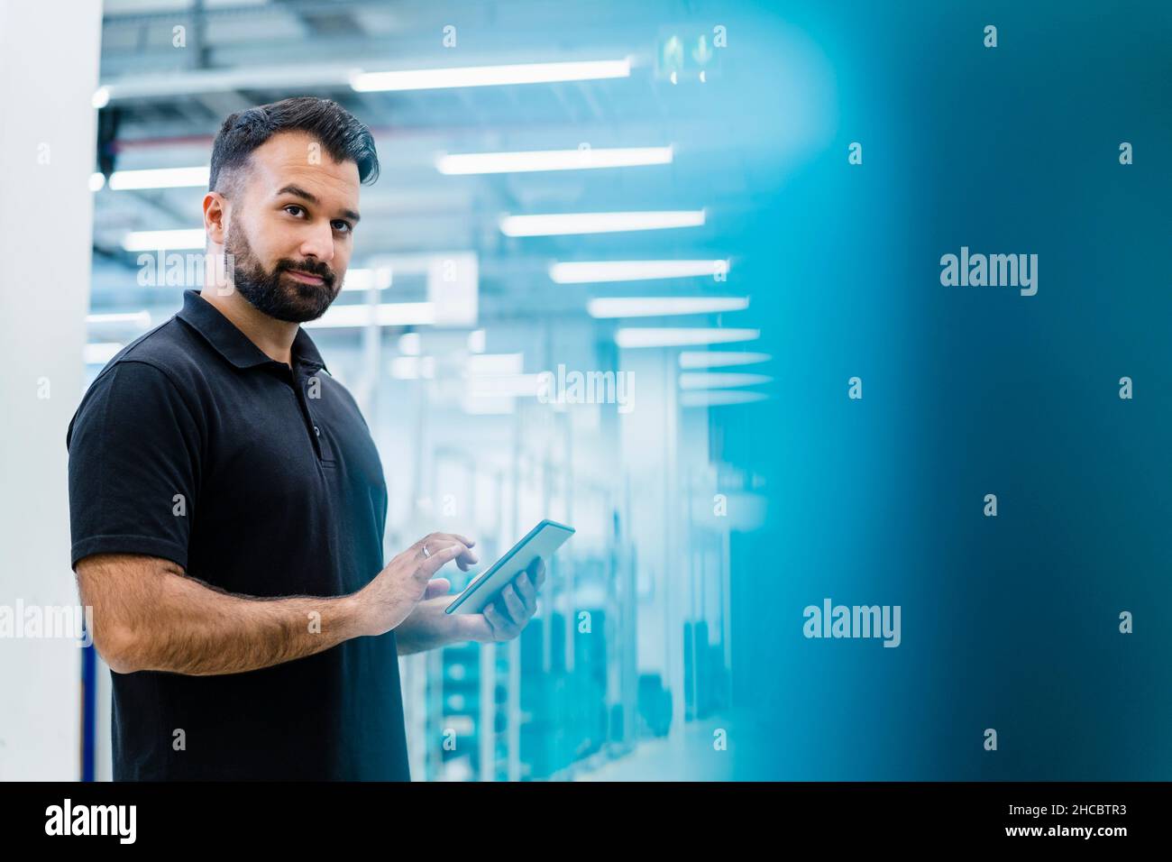 Bearded engineer holding tablet PC at warehouse Stock Photo - Alamy