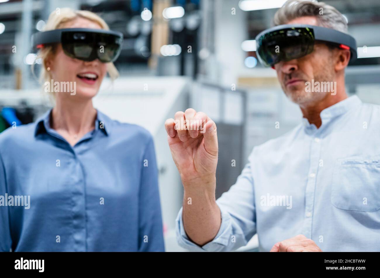 Businessman gesturing and using augmented reality eyeglasses at ...