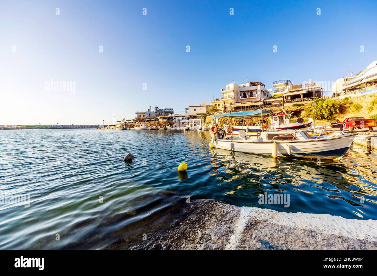Greece, Crete, Sissi, Edge of coastal village with boat in foreground ...
