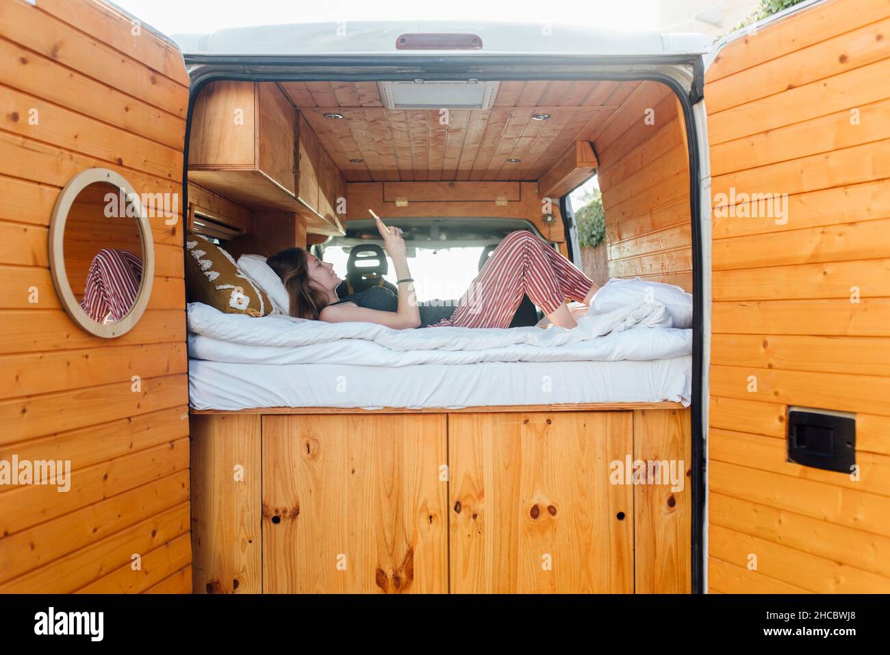Woman using mobile phone lying on bed in camper trailer Stock Photo - Alamy