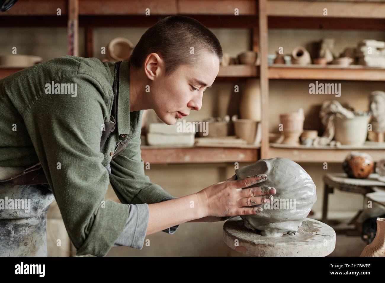 Young woman making human face from clay, she creating clay sculptures ...