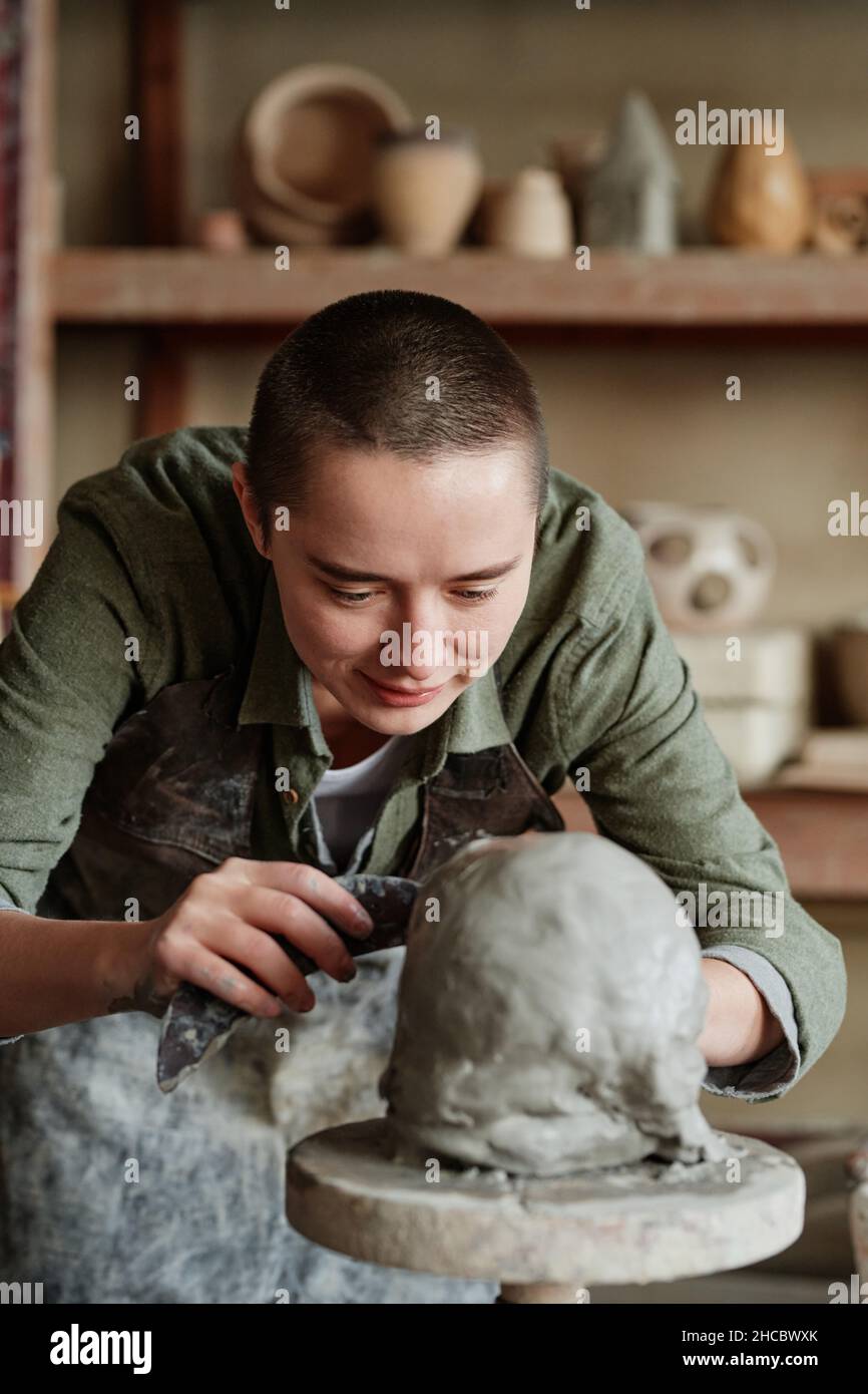 Professional potter making a form of bowl from clay in pottery workshop ...