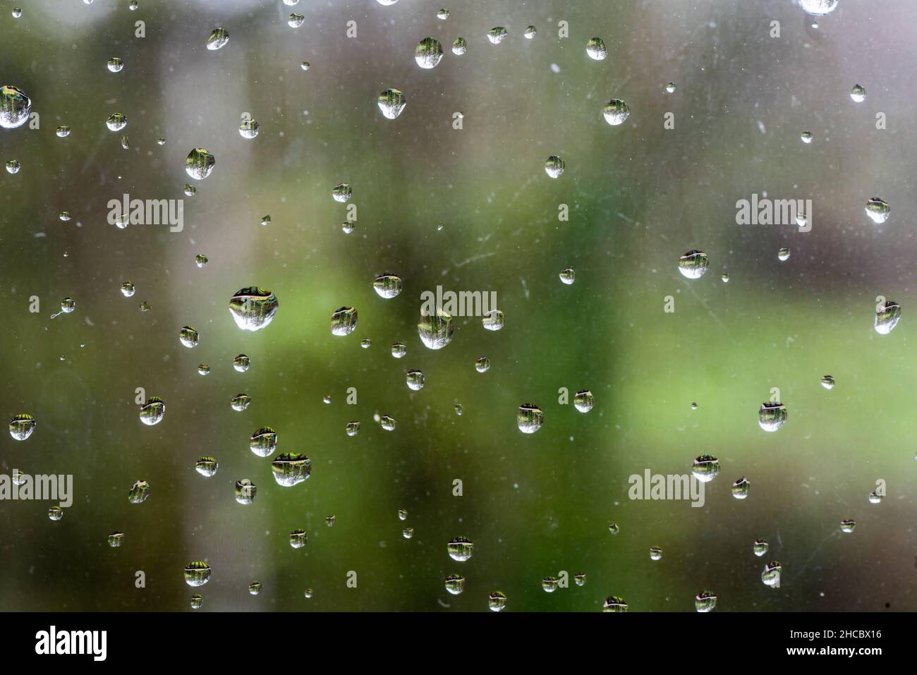 Raindrops on a Window with the Garden Showing in each Raindrop ...