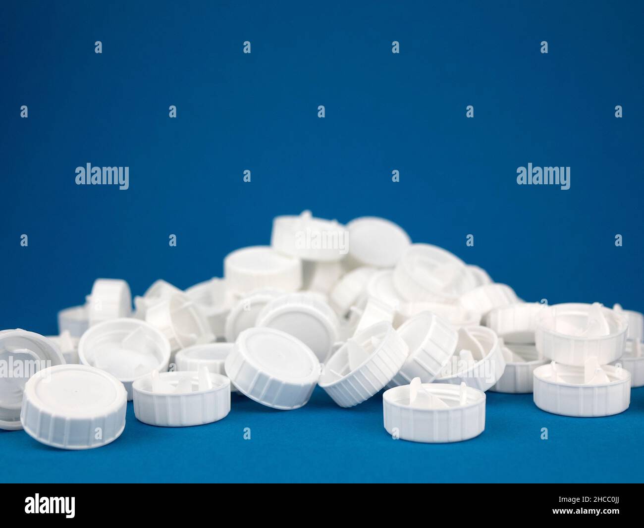 Pile of white plastic screw caps on the blue background, selective ...