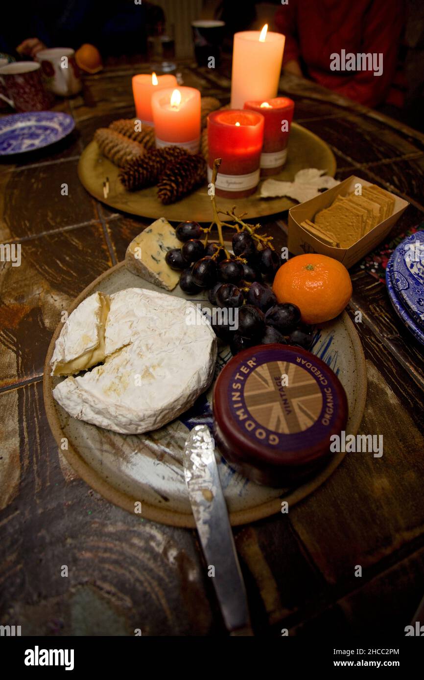 A selection of cheese on table with candles and open fire Stock Photo ...