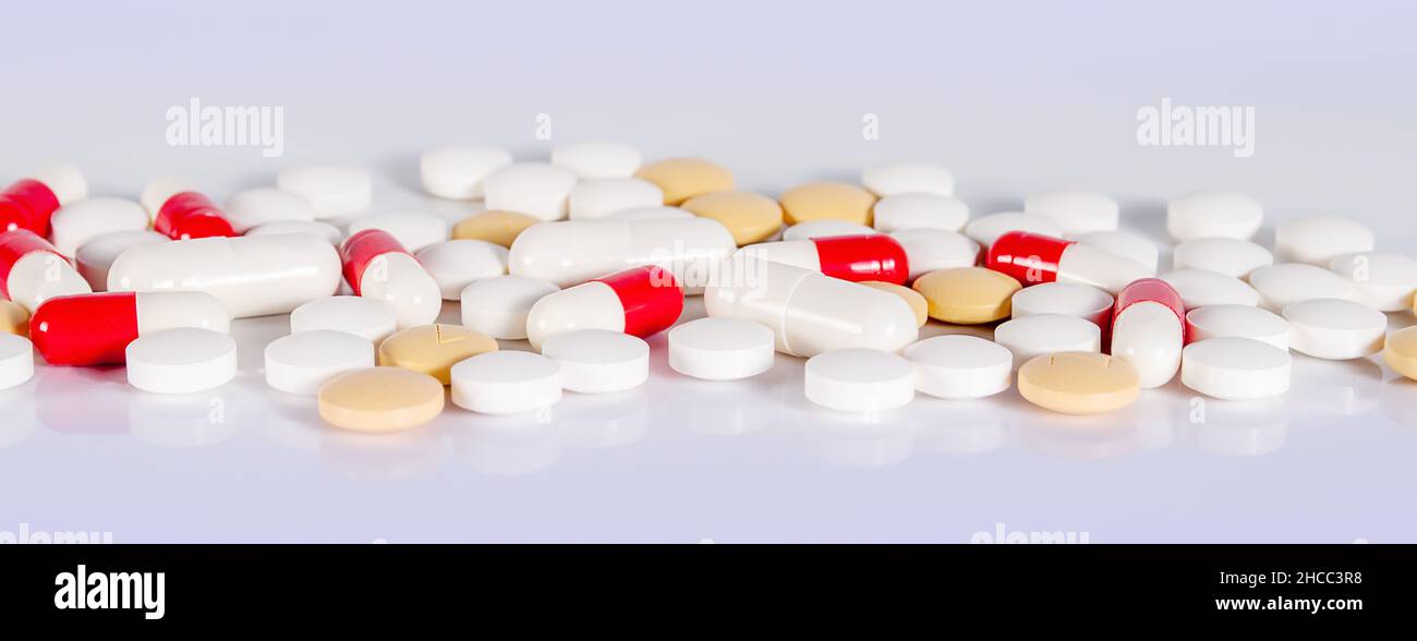 different kind of pills, tablets and capsules on light blue background ...